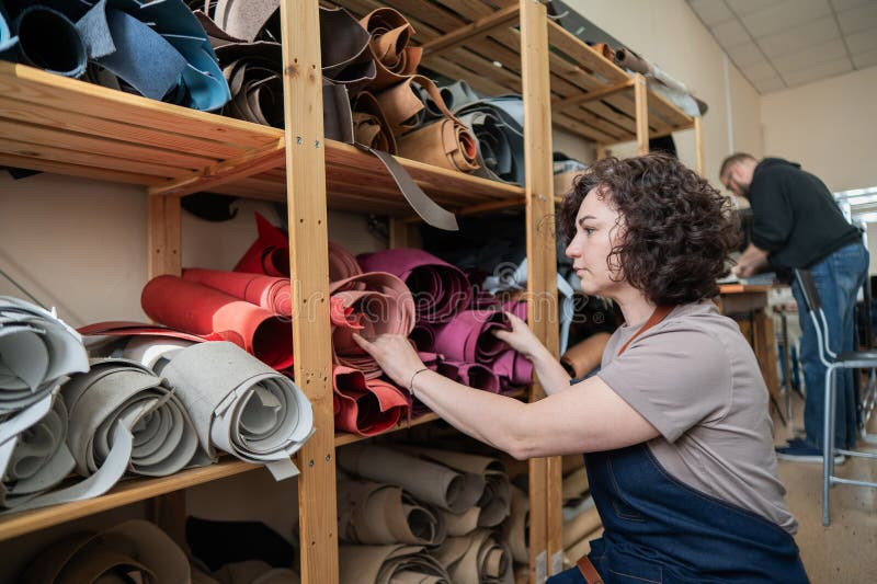 Woman Leatherworker Selects a Roll of Leather in the Workshop. Stock ...