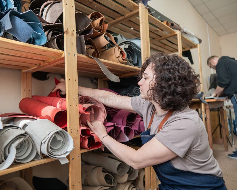 Woman Leatherworker Selects a Roll of Leather in the Workshop. Stock ...