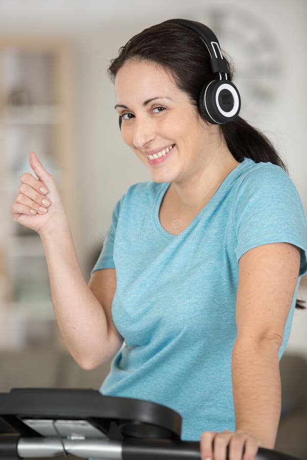 Woman Listening To Music while Using Exercise Machine Stock Photo ...