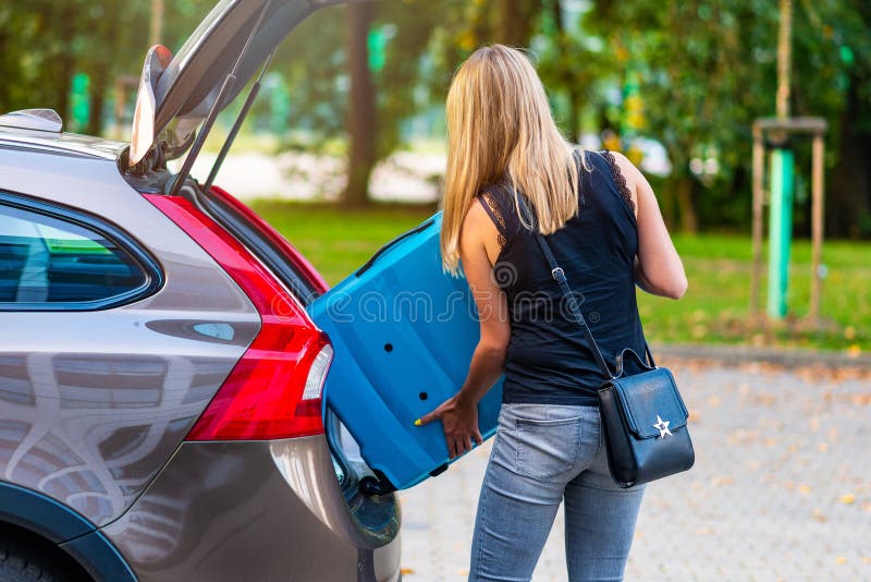 Woman Loading Two Blue Plastic Suitcases To Car Trunk. Stock Image ...