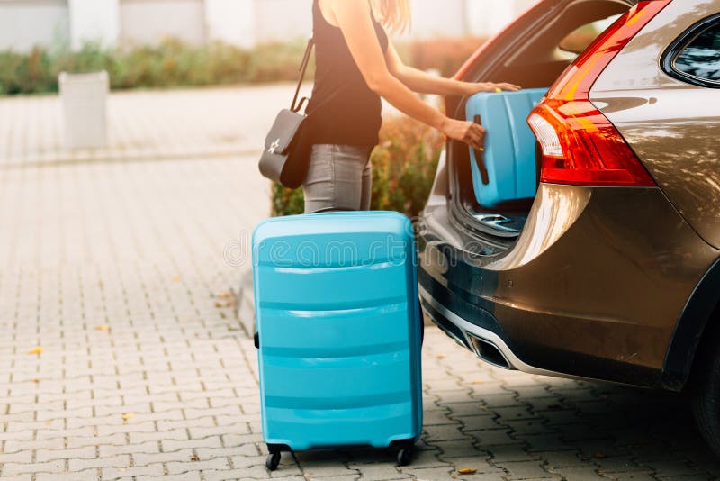 Woman Loading Two Blue Plastic Suitcases To Car Trunk. Stock Image ...