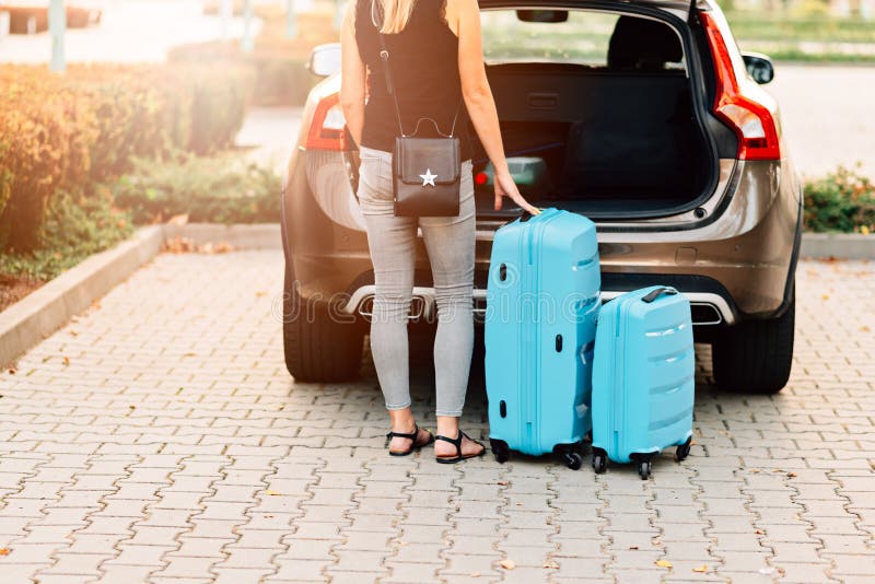 Woman Loading Two Blue Plastic Suitcases To Car Trunk. Stock Image ...