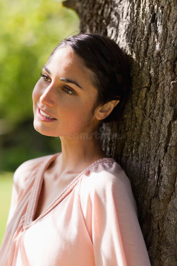 Woman Looking into the Distance while Sitting Against a Tree Stock ...