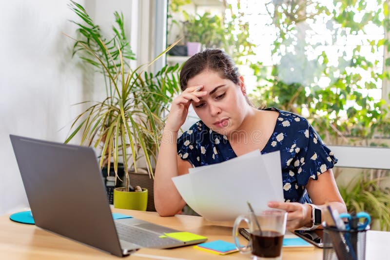 A Woman Looking at Paperwork at the Office, Stressed Stock Photo ...