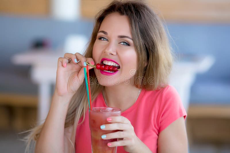 A Woman Looks at the Camera and Drinks a Cocktail and Snacks it with a ...