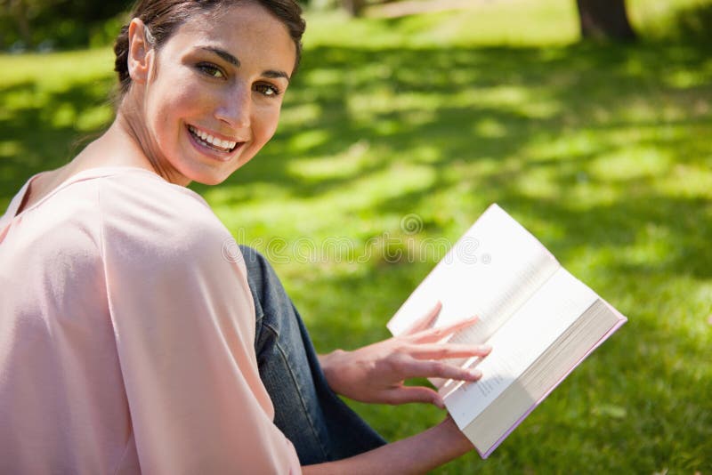 Woman Looks To Her Side while Reading a Book in the Grass Stock Image ...