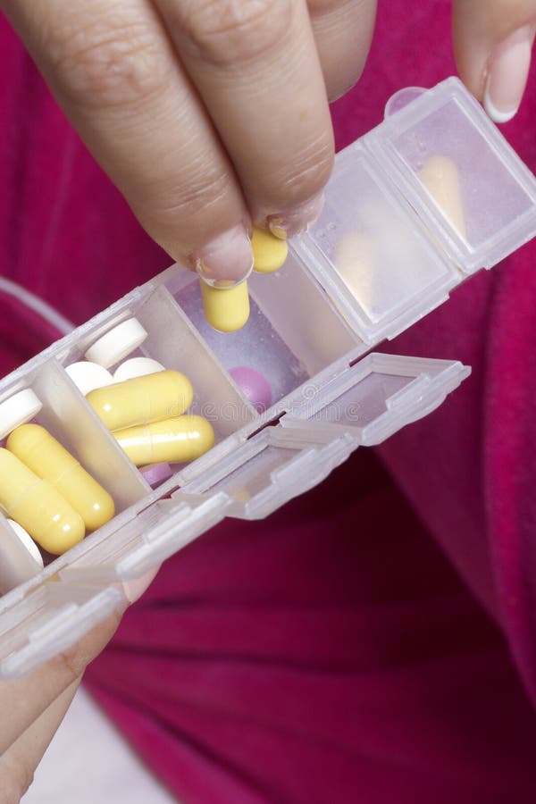 Woman Lying in Bed Taking Pills from a Special Container. Holds a ...
