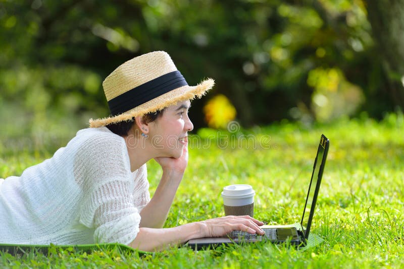 Woman Lying on Green Grass Using Laptop Computer in the Park Stock ...
