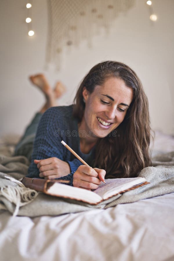 Woman Lying on Her Bed Writing in Her Notebook Stock Photo - Image of ...