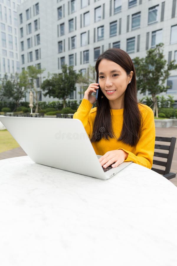 Woman Make a Call by Cellphone and Use of the Notebook Computer Stock ...