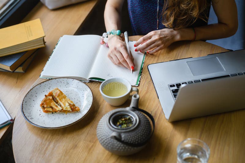 A Woman Makes a Note in Her Notebook while Sitting in a Cafe Stock ...