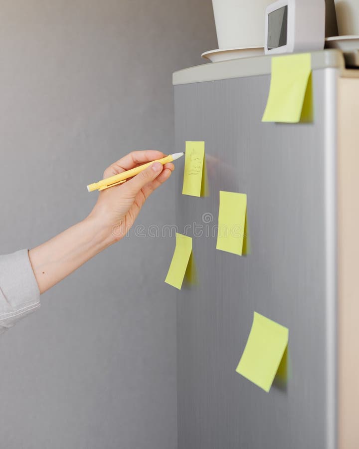 A Woman Makes Notes on Colored Stickers on the Refrigerator. a Reminder ...