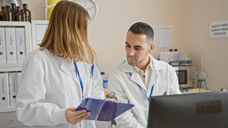 A Woman and a Man in Lab Coats Examine a Document Together in a ...