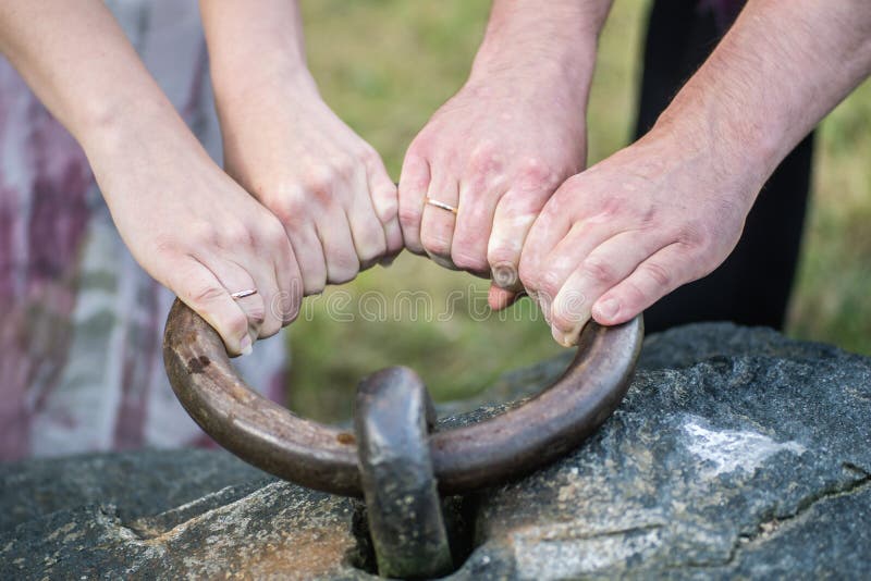 Woman and Man`s Arms with Wedding Rings Pull a Large Metal Ring Stock ...