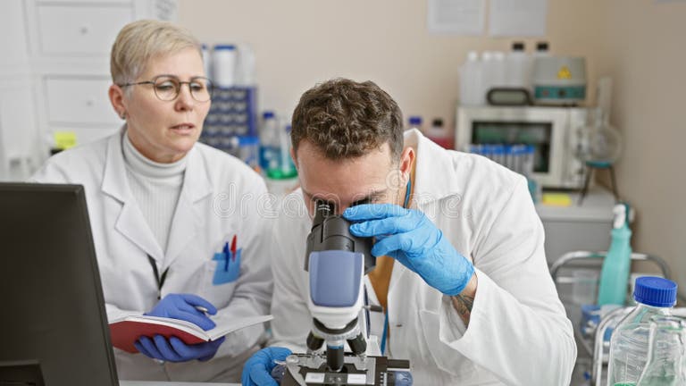 A Woman and Man, Scientists, Work Together in a Laboratory, Examining ...