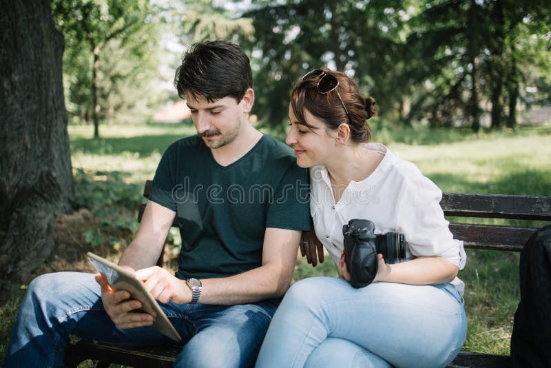 Woman and Man Sitting on Bench and Looking at Tablet`s Display Stock ...