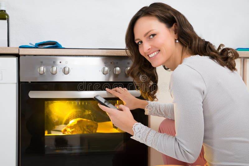Woman with Mobile Phone while Cooking Chicken Stock Photo - Image of ...
