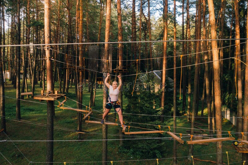 A Woman Overcomes an Obstacle in a Rope Town. a Woman in a Forest Rope ...