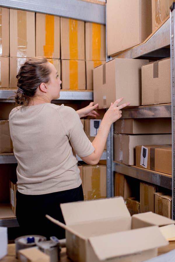 A Woman Packs Boxes, Puts the Box on the Rack. Delivery of Goods Stock ...