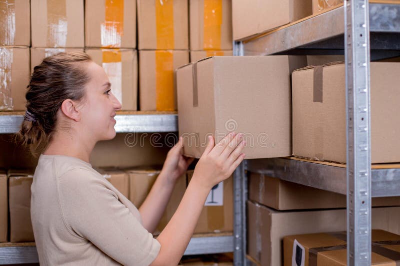 A Woman Packs Boxes, Puts the Box on the Rack. Delivery of Goods Stock ...