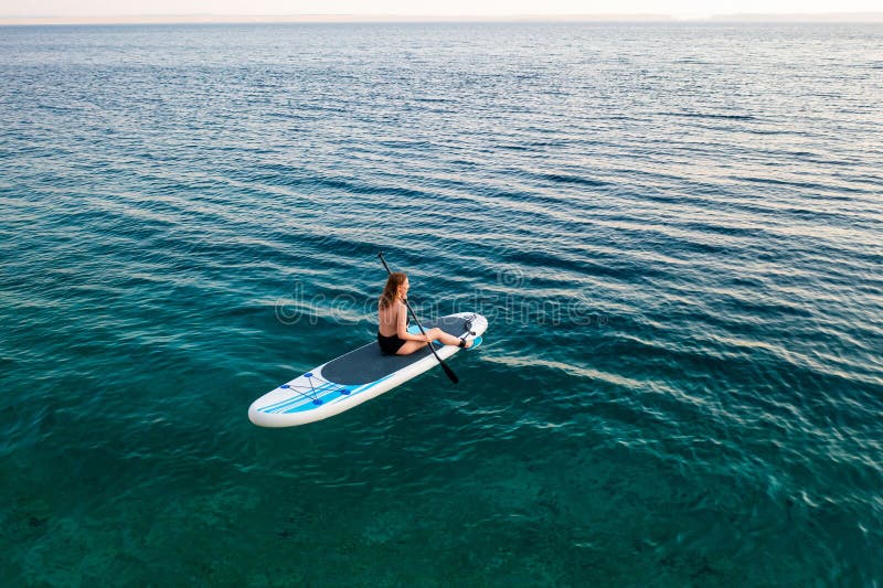 Woman Paddle Boarding on Clear Water during a Calm Twilight Hour at the ...