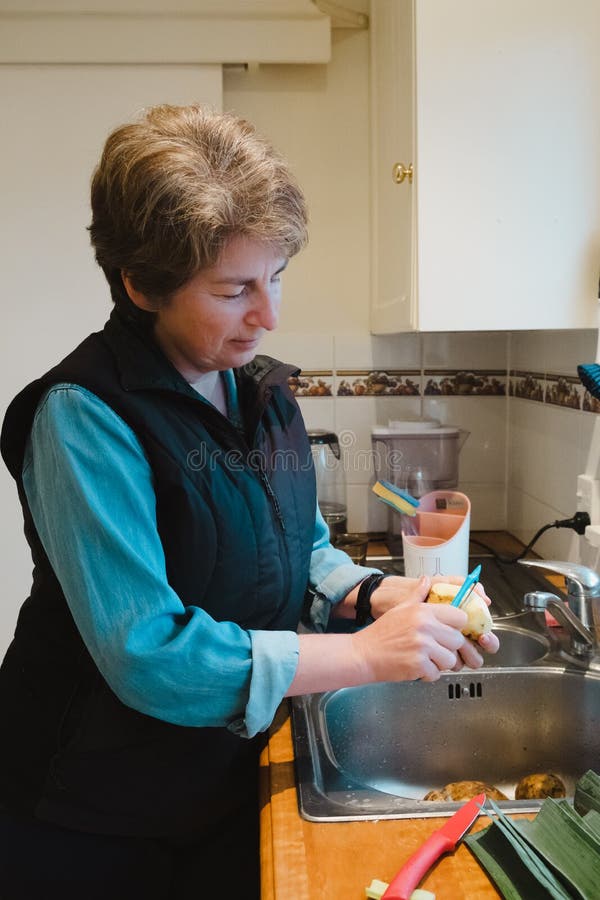 A Woman Peeling Potato on a Kitchen with Wooden Bench Stock Photo ...