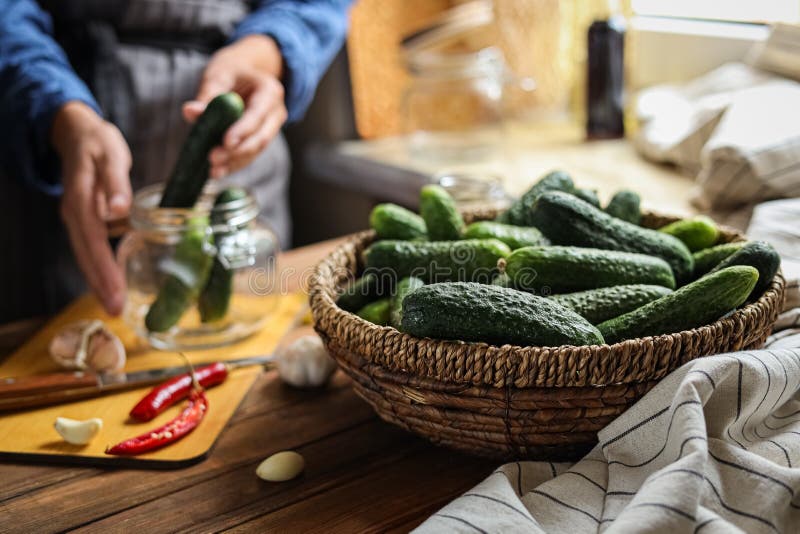 Woman Pickling Vegetables at Table, Focus on Basket with Cucumbers ...