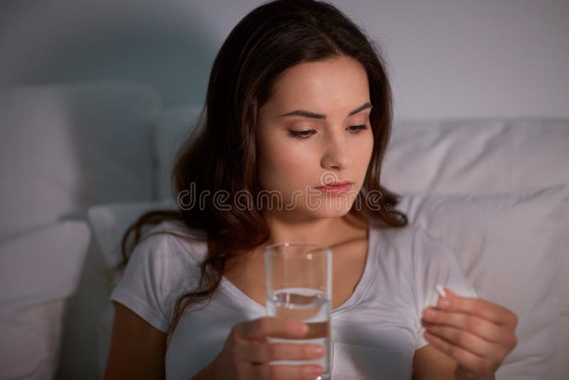 Woman With Pill And Glass Of Water In Bed At Home Stock Image Image