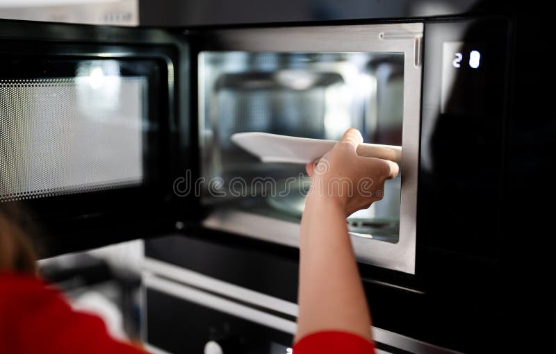Woman Placing a Plate into the Microwave Stock Photo - Image of hand ...