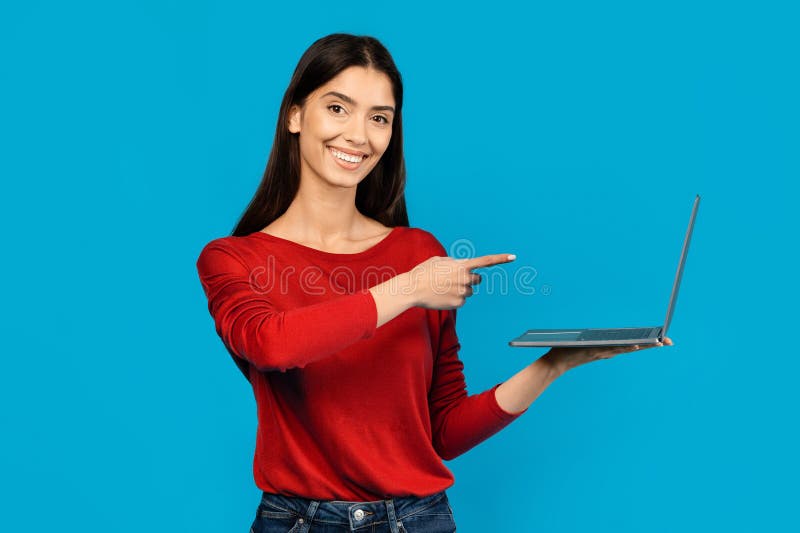 Woman Pointing at Laptop in Hands, Standing on Blue Background Stock ...