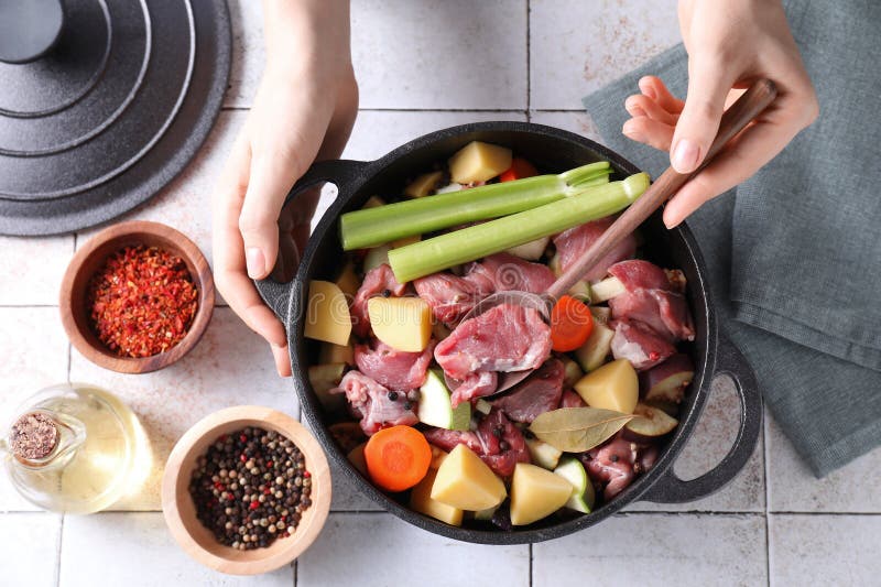 Woman Preparing Stew with Vegetables and Meat at White Tiled Table, Top ...