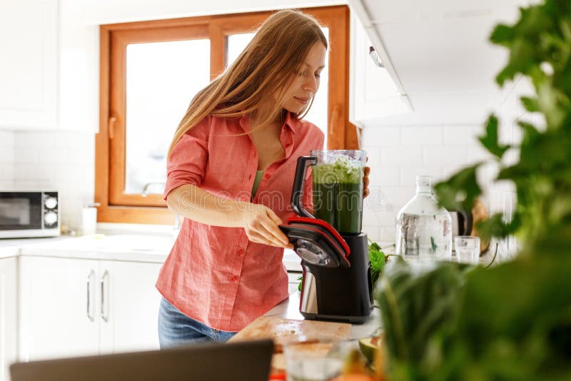 Cheerful Young Woman Making Smoothie Using Blender in the Kitchen Stock ...