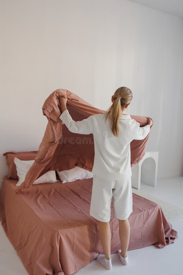 A Woman is in the Process of Making a Bed in a Cozy Bedroom Stock Photo ...
