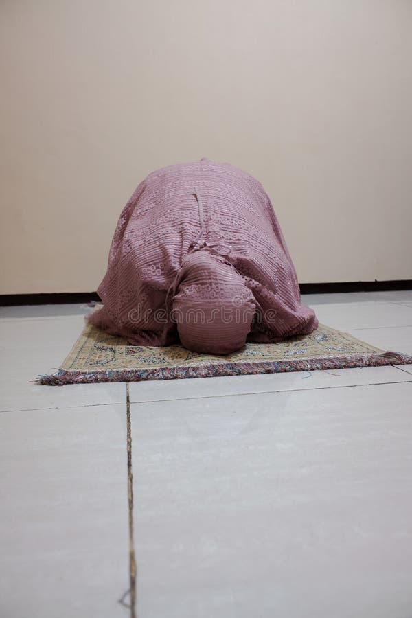 A Woman is Prostrating for Prayer Using a Pink Mukena Stock Image ...