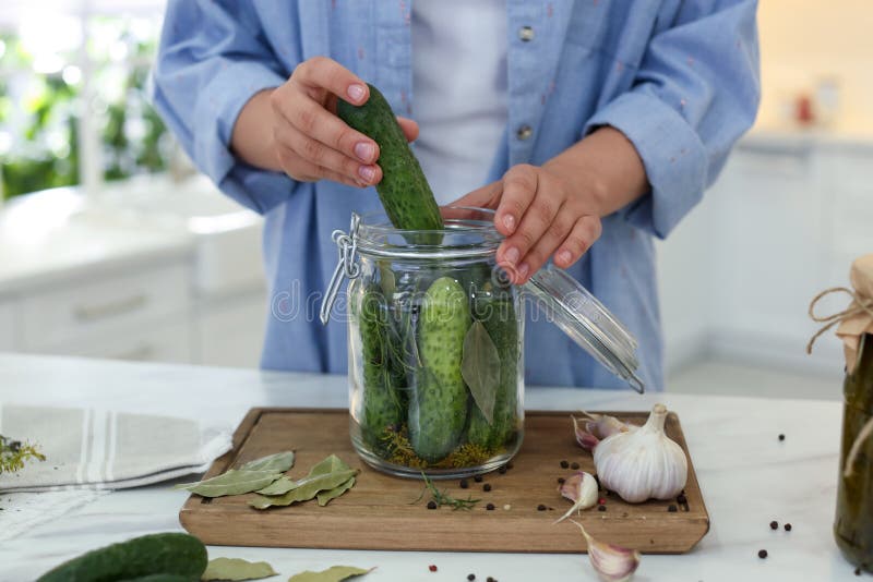 Woman Putting Cucumber into Pickling Jar at Table in Kitchen, Closeup ...