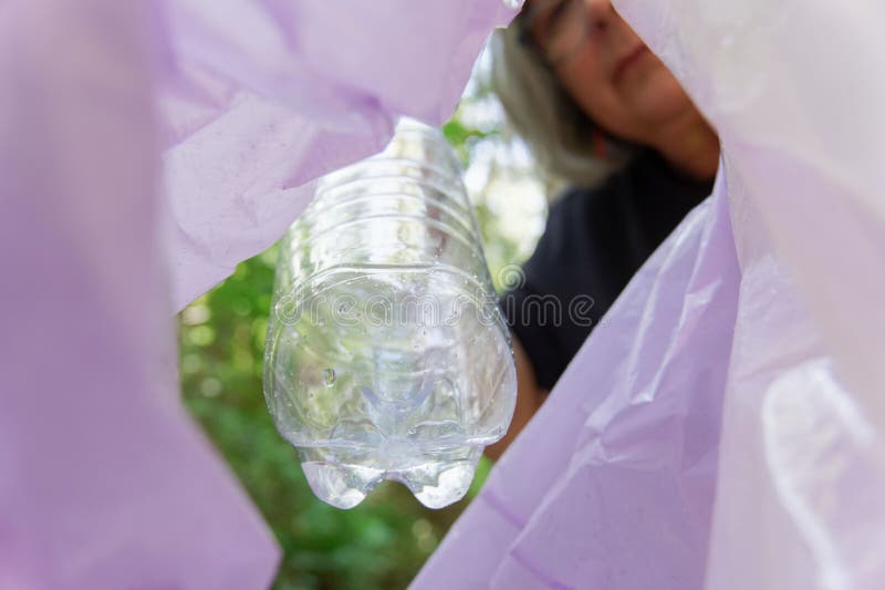 Woman Putting a Plastic Bottle in a Garbage Bag As Seen from Inside the ...