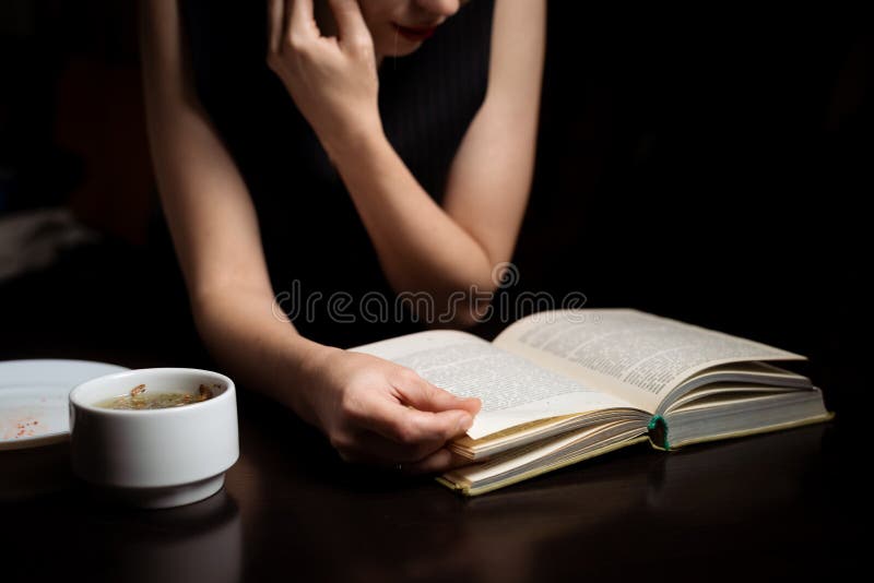 A Woman is Reading a Book in the Dark. Sits by the Table Stock Image ...