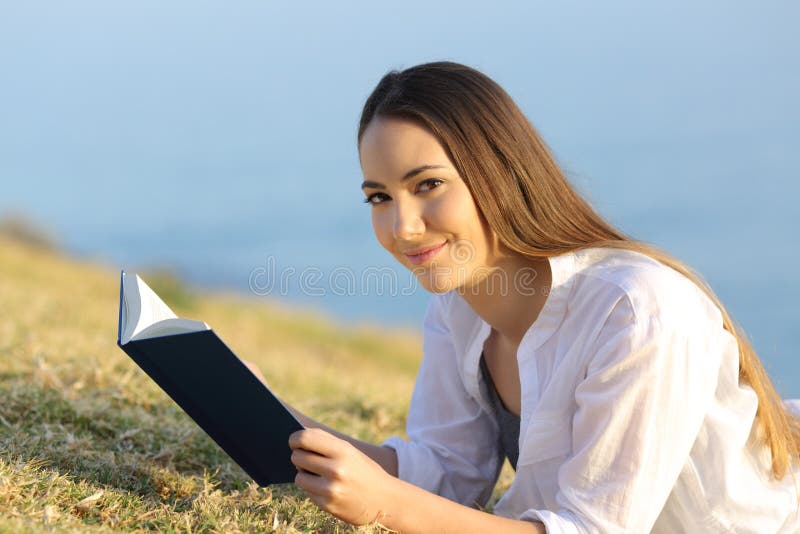 Woman Reading a Book Looking at Camera on the Grass Stock Photo - Image ...