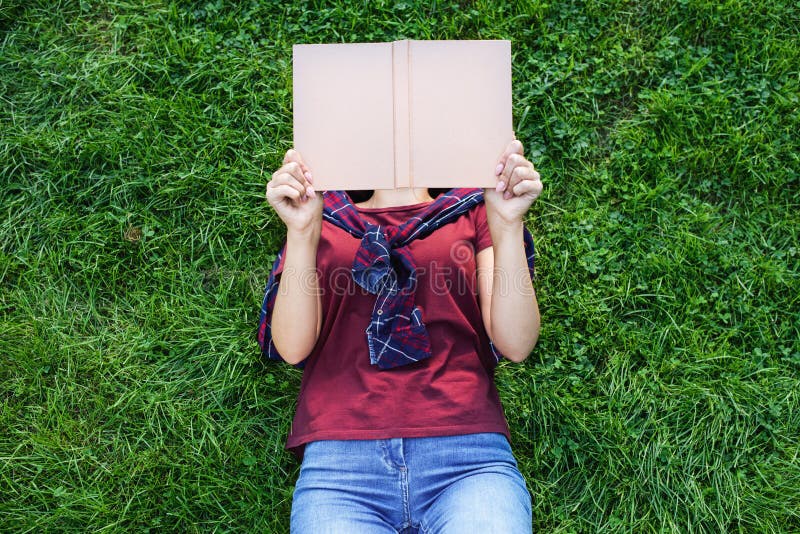 Woman Reading Book while Lying on Green Grass Outdoors, Top View Stock ...