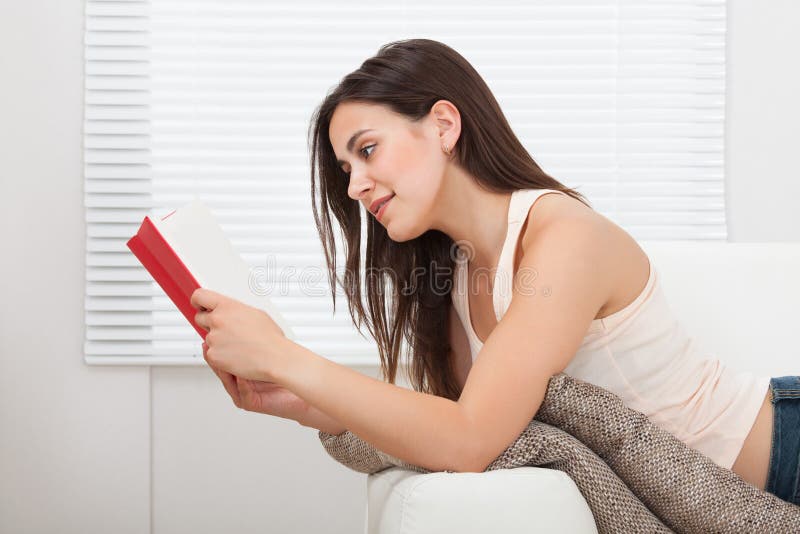 Woman Reading Book while Lying on Sofa Stock Photo - Image of ...