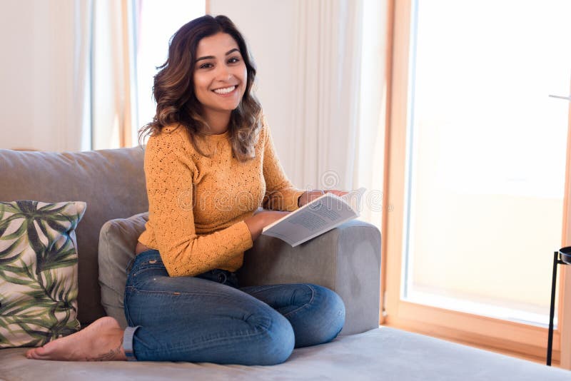Woman reading book on sofa stock photo. Image of comfortable - 170602986