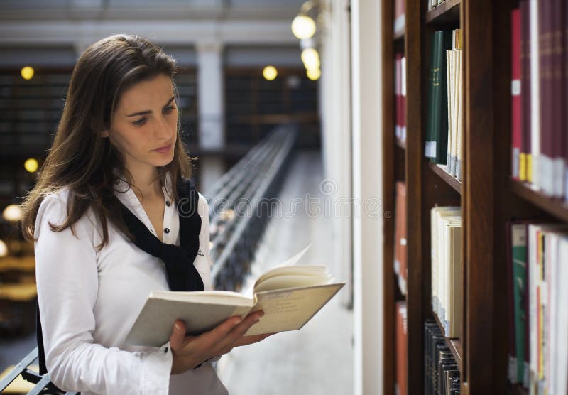 Woman reading at bookshelf stock image. Image of beauty - 13731767