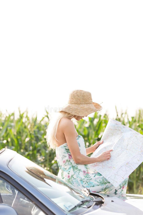 Woman Reading Map while Leaning on Convertible Against Clear Sky Stock ...