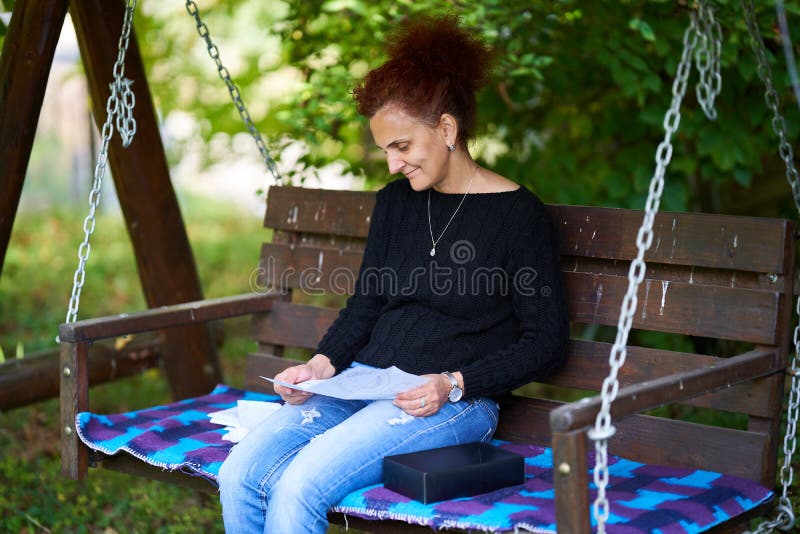 Woman reading in a swing stock image. Image of letter - 233063921
