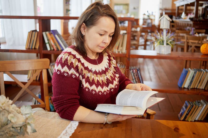Woman Reads Book Sitting at Table in Stock Photo - Image of literacy ...