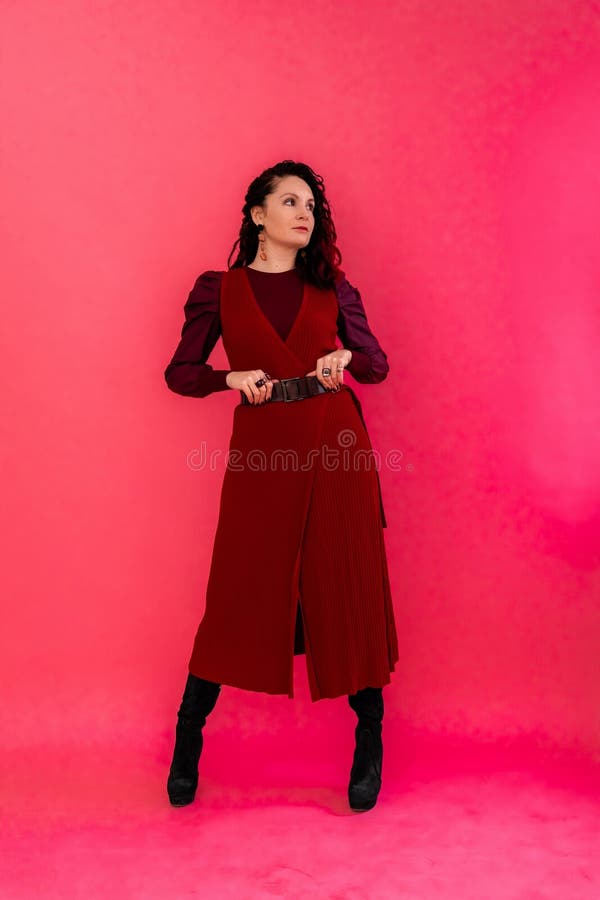 A Woman In A Red Dress Poses For The Camera She Is Wearing Black Boots
