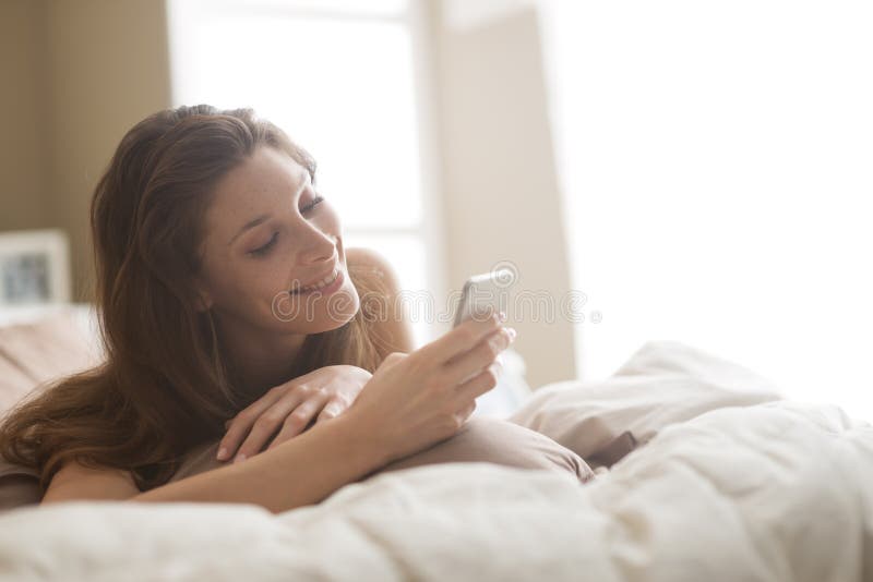 Disappointed Sad Woman Holding Mobile Phone while Laying on Bed Stock ...