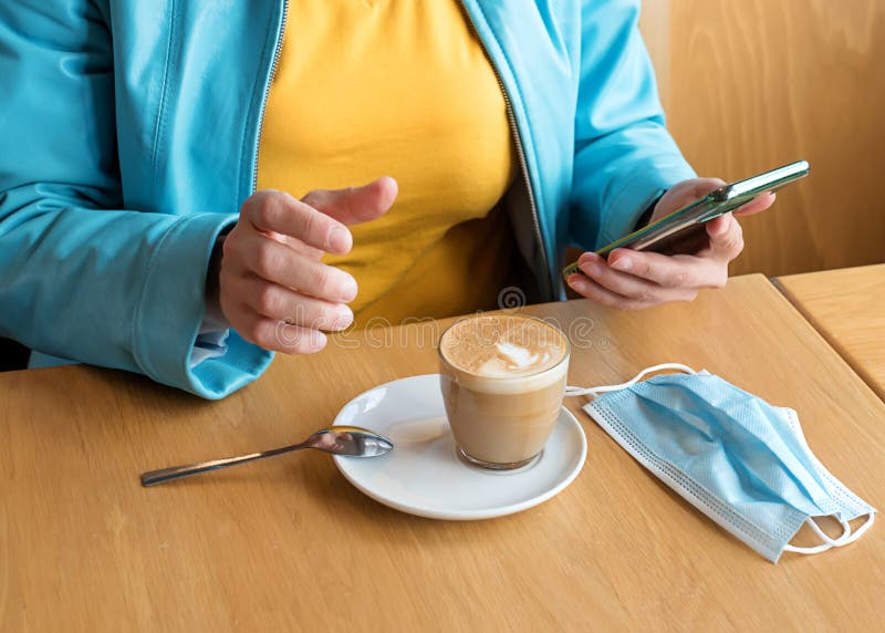 Woman Removing the Mask, Drinking Coffee and Chating in the Cafe during ...
