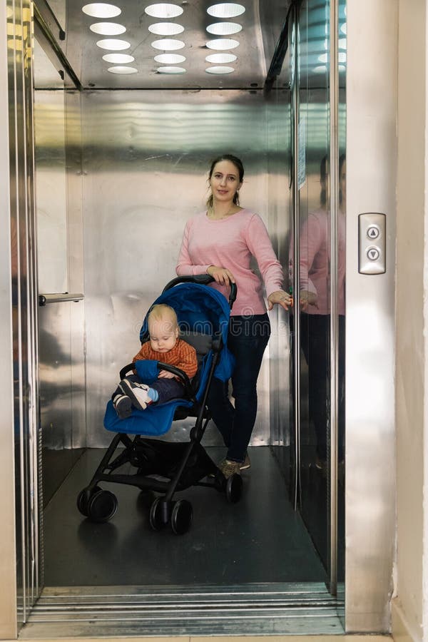 Woman Rides in an Elevator with a Baby in a Stroller in a Mall. Stock ...