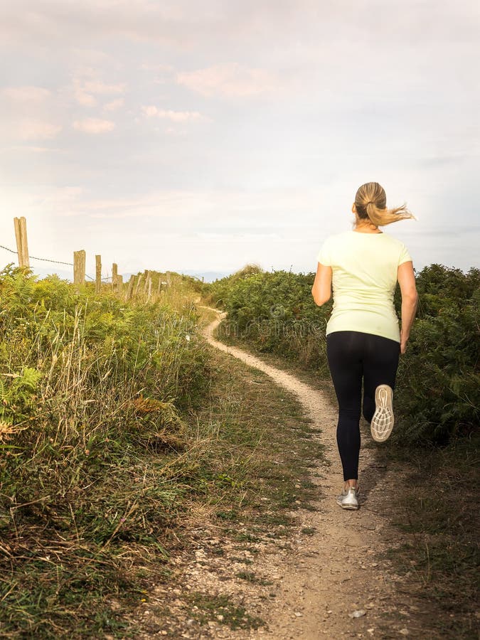 Woman Running Along a Path at Sunset Stock Photo - Image of copy ...